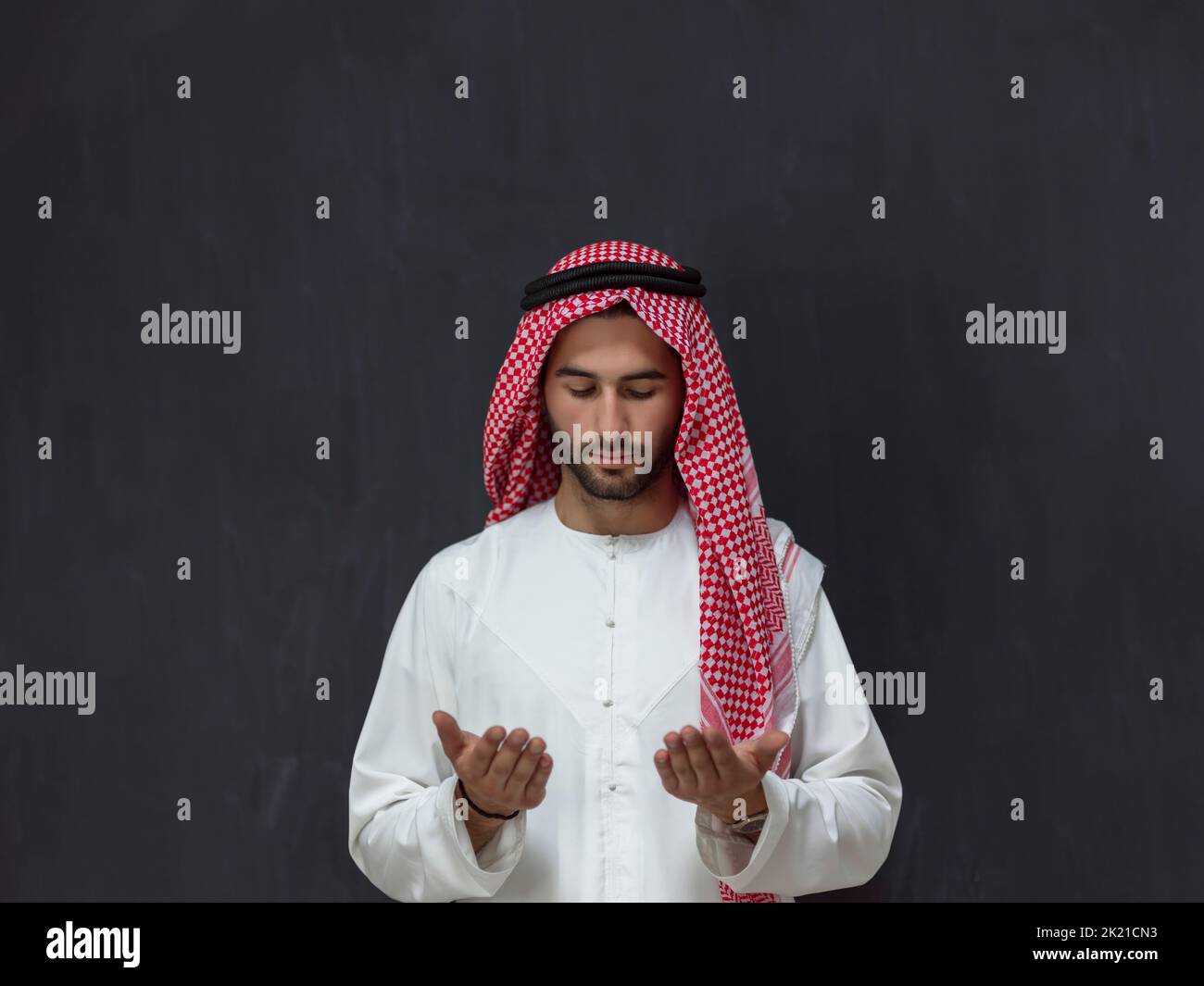 A young Arabian man in traditional clothes making a traditional prayer ...
