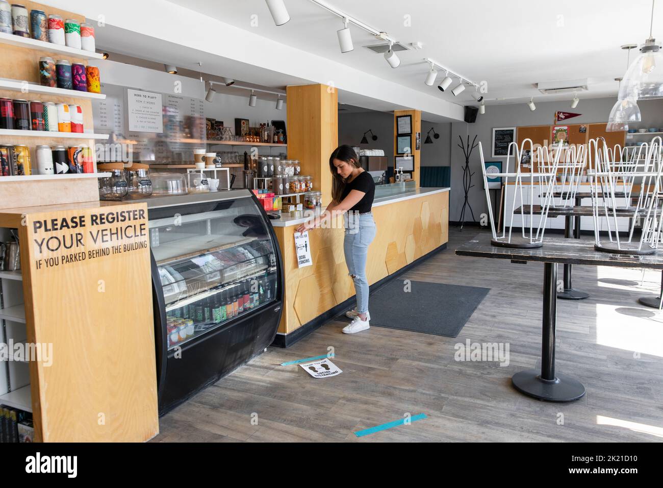 Young woman putting safety distance poster on cafe counter Stock Photo ...
