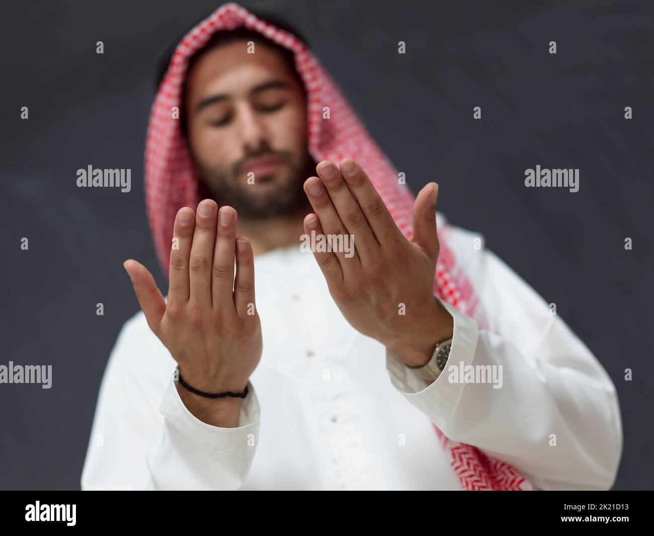 A young Arabian man in traditional clothes making a traditional prayer ...