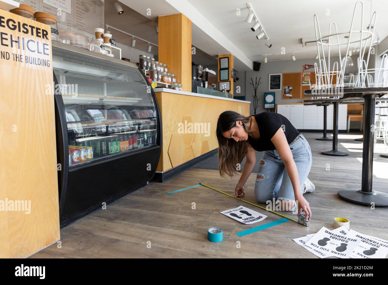 Young woman measuring safety distance on cafe floor during covid Stock ...