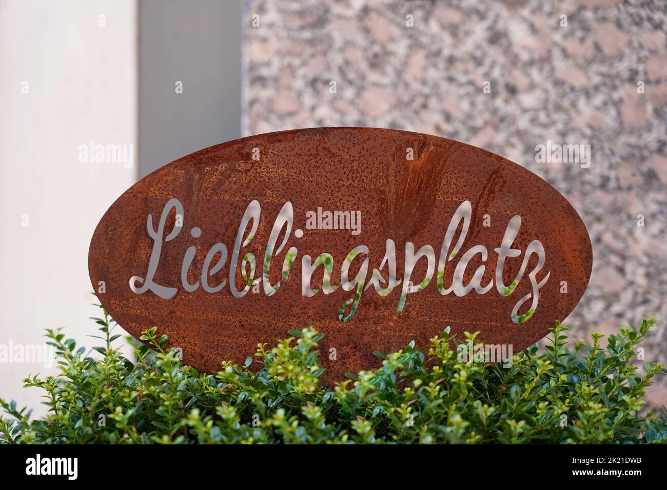 A wooden oval shape banner on the grass with carvings of german word ...