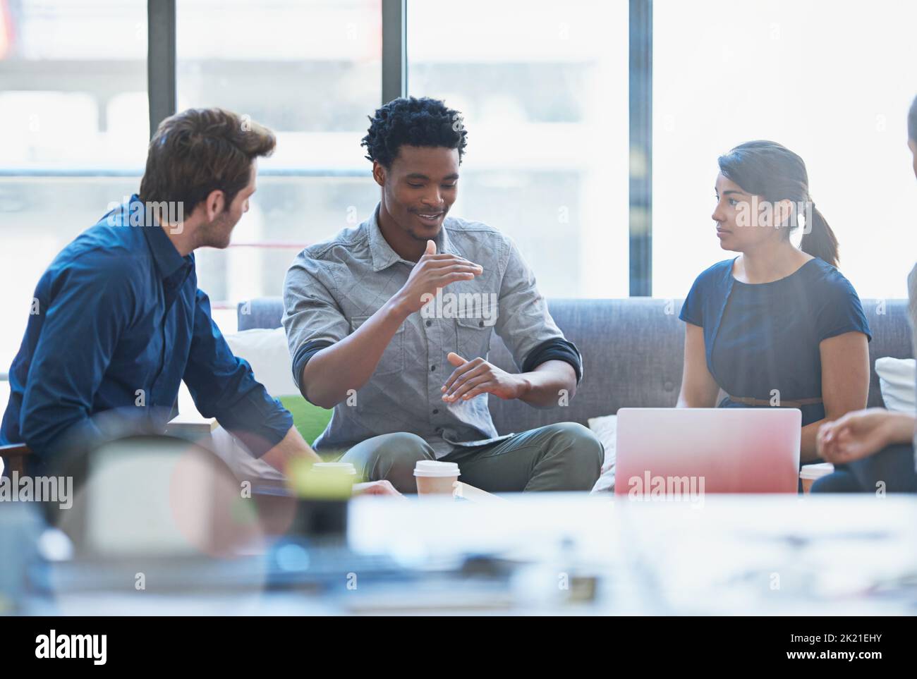 Building on his ideas. a group of office workers talking together in a ...