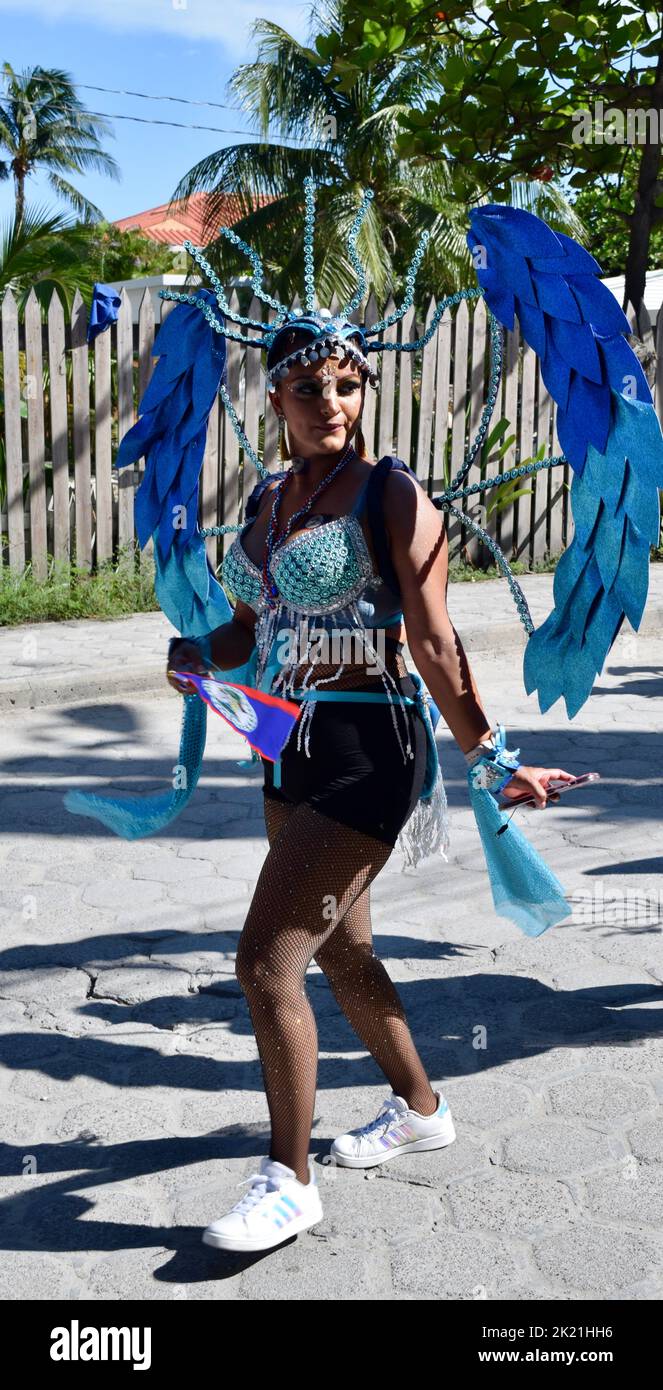 A lone young Belizean woman in a blue, winged costume walking in the ...