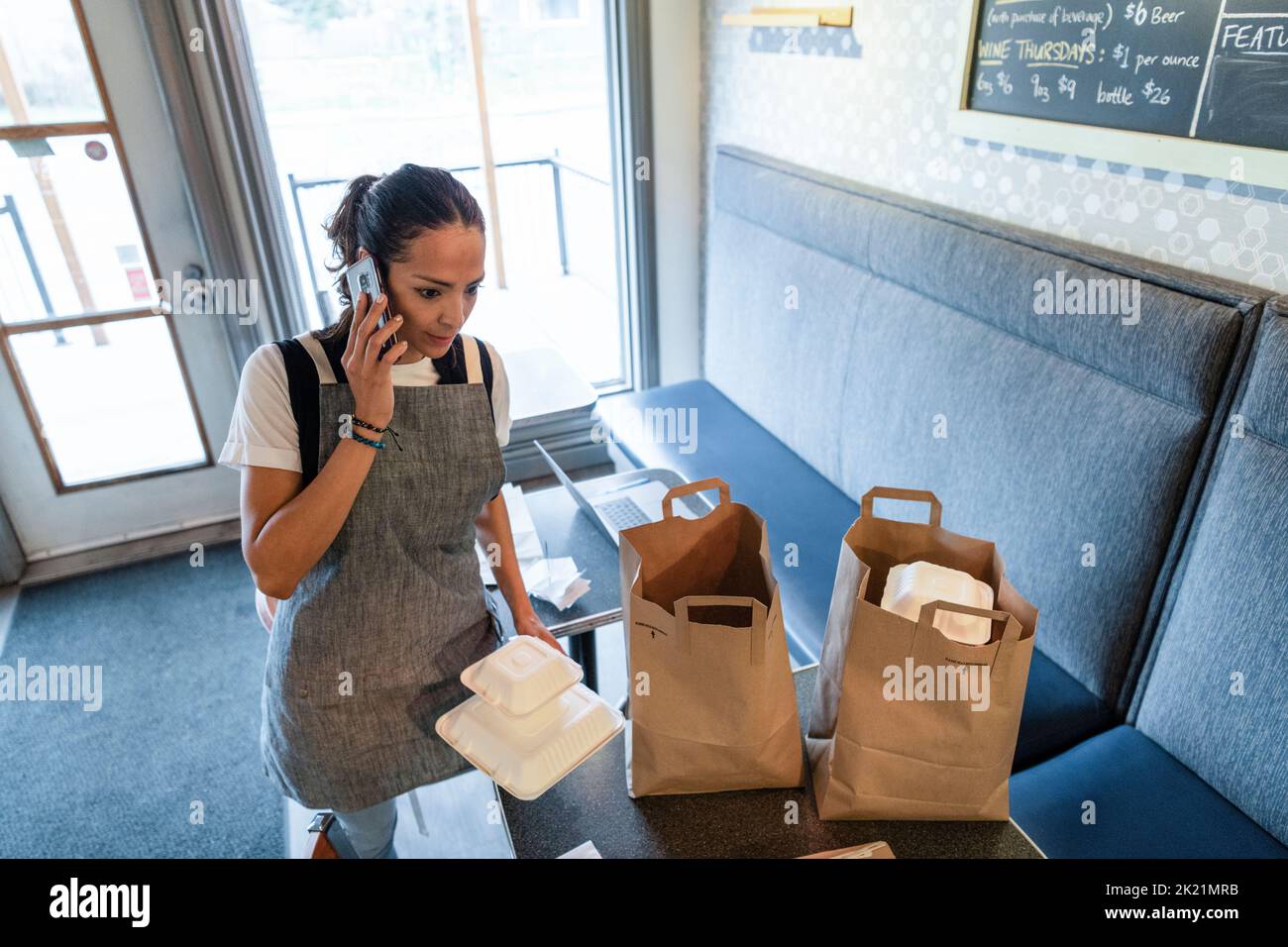 Female business owner bagging takeout orders in cafe Stock Photo - Alamy
