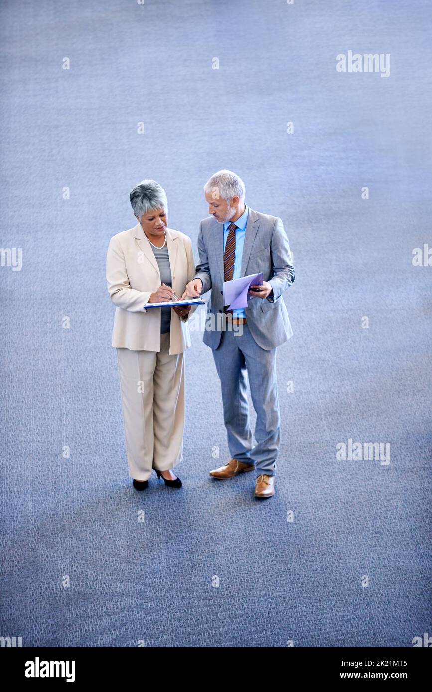 Heres how it works. Full length shot of two colleagues looking over a ...