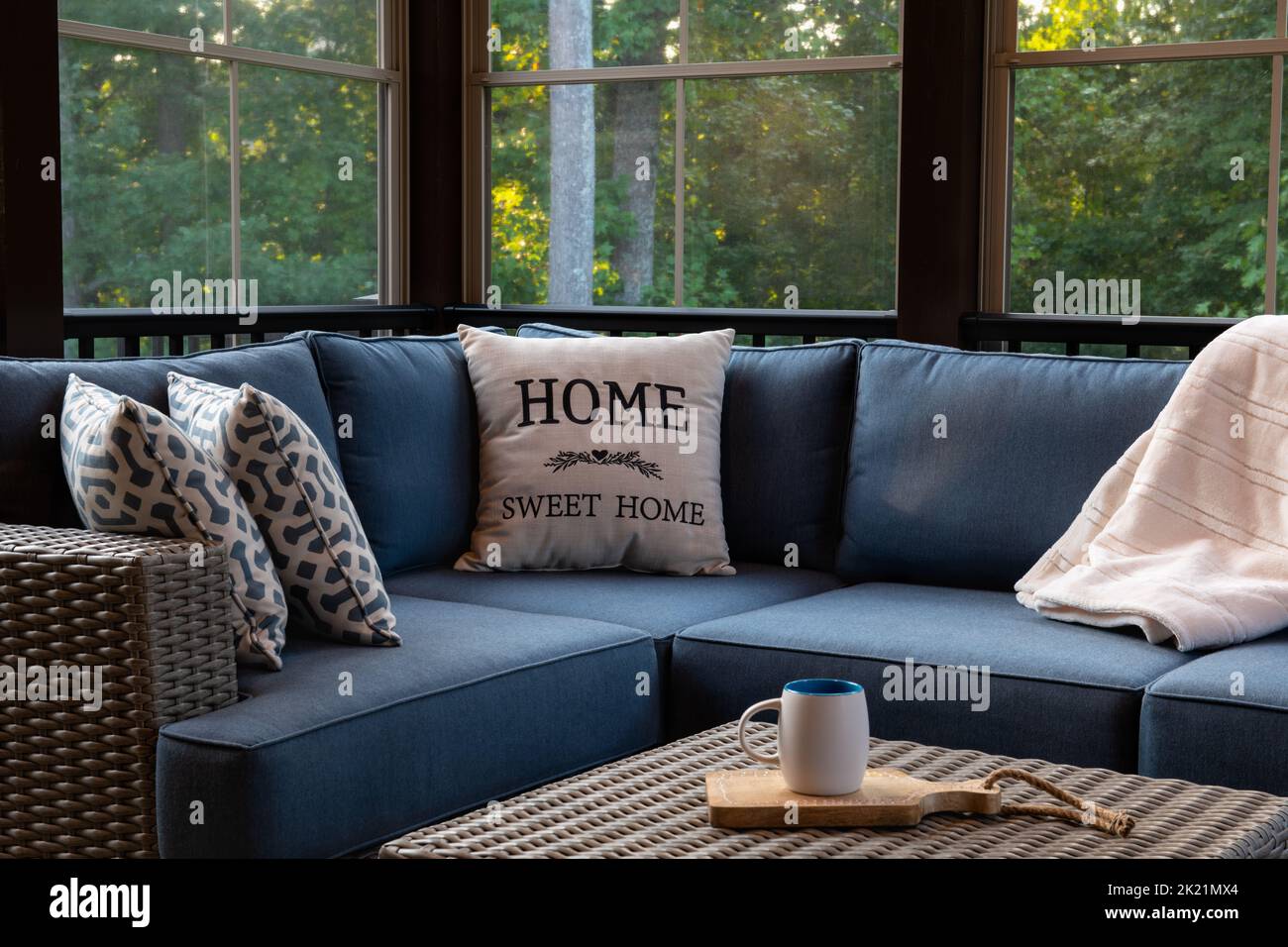 A cozy corner of an outdoor living space with modern porch windows, patio furniture, cushions ...