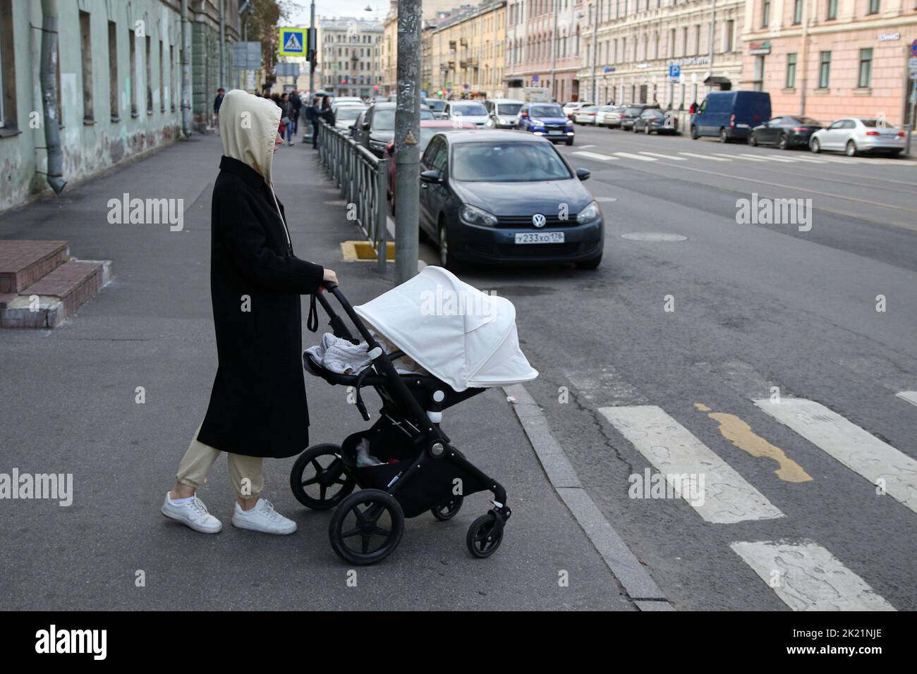 A mother with a baby in a stroller crosses the road in the center of St ...