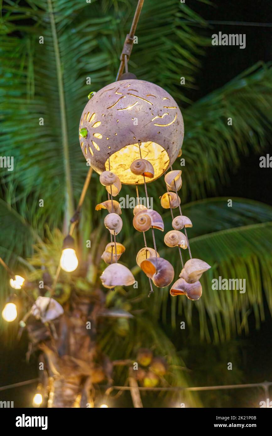 A decorative lamp and shade with snail shells dangling below lights up ...