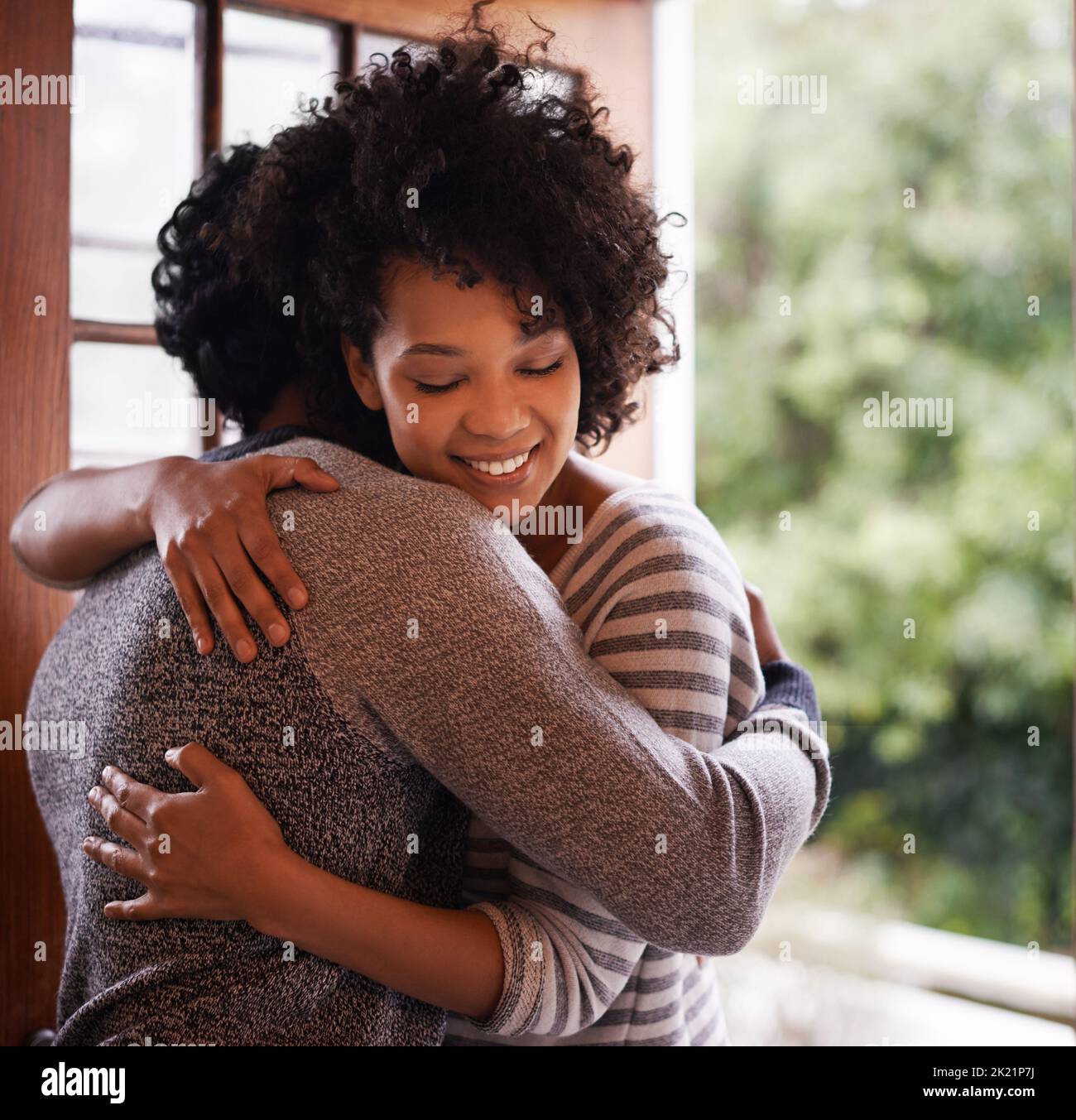 Greeting her with a warm embrace. a young woman greeting her husband at the door Stock Photo - Alamy