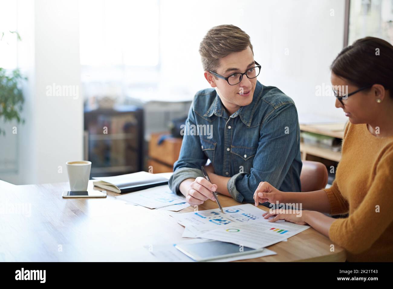 Ideas are flowing. two young colleagues working together at a desk in ...