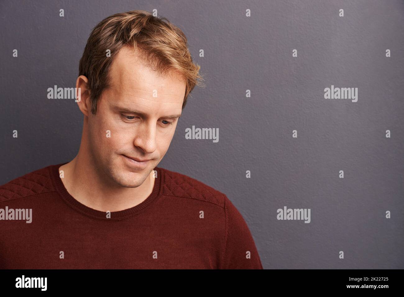 Thinking all the thoughts. a handsome young man looking down in a ...