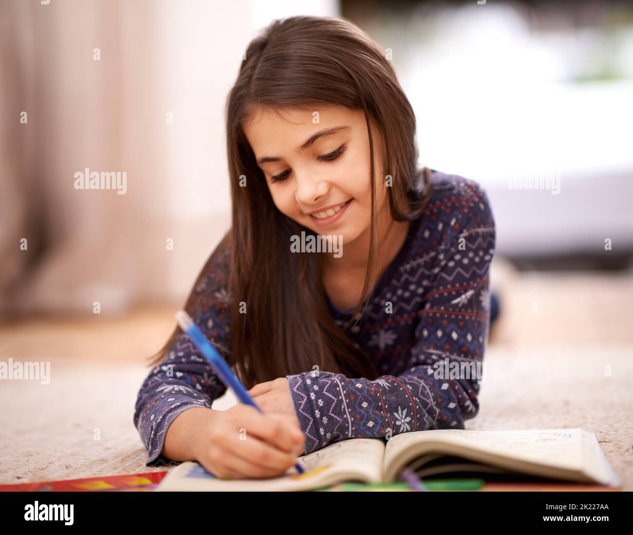 Creating from a young age. A young girl coloring while lying on the ...
