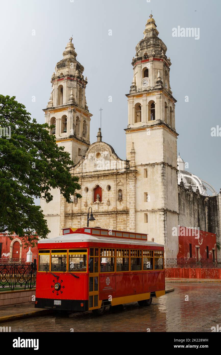 Red trolley in front of the towering Cathedral of Campeche in Mexico ...