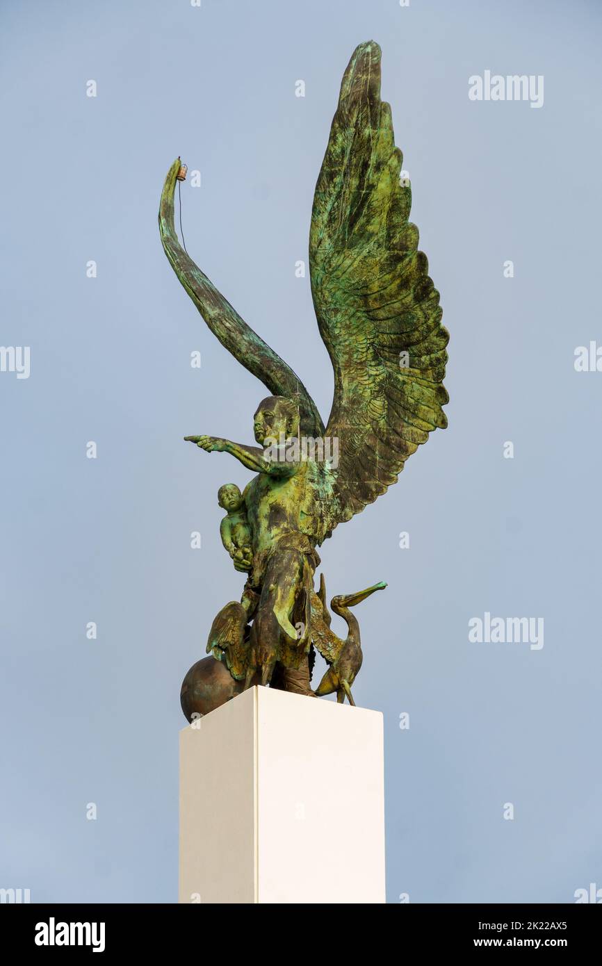 Weathered statue of an angel, a baby, and a pelican atop a pedestal in ...