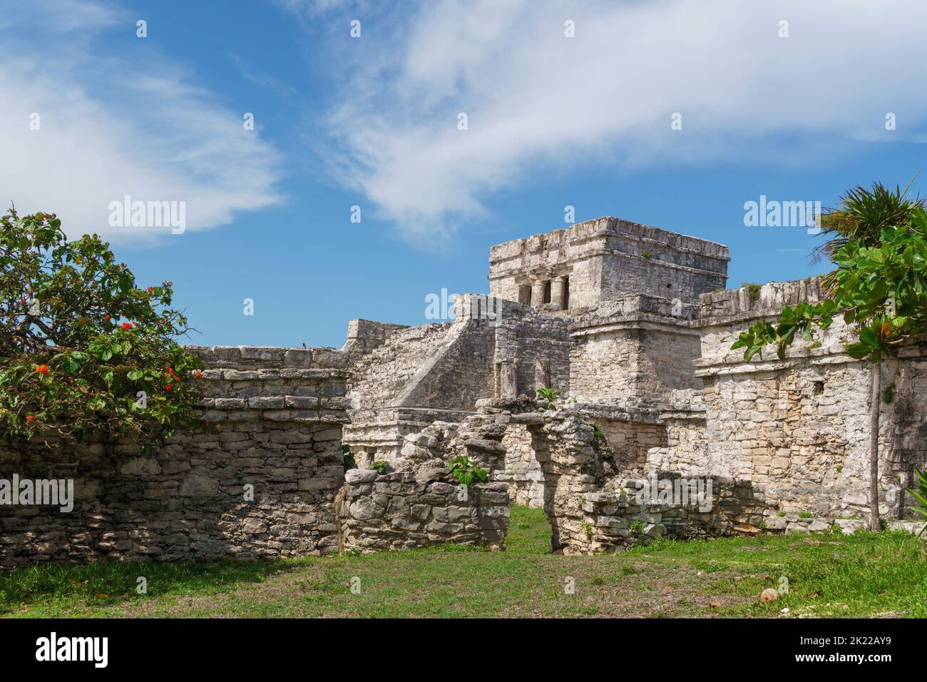Stone arch and flowering trees in front of the ancient Mayan El ...