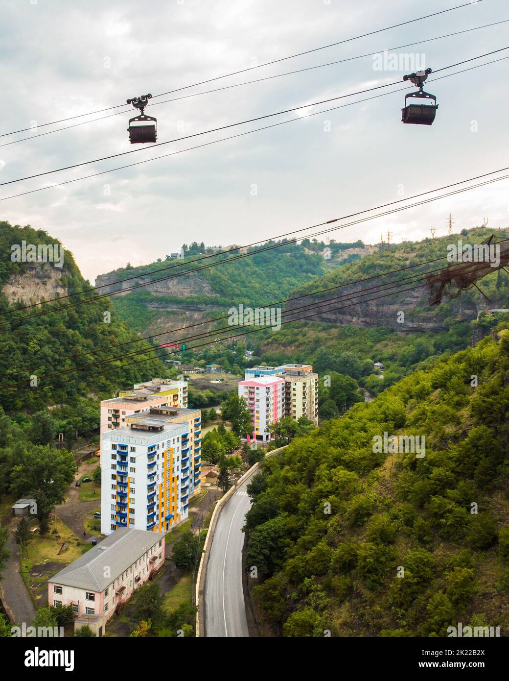 Aerial rising view ropeway with metal buckets with load above road in ...