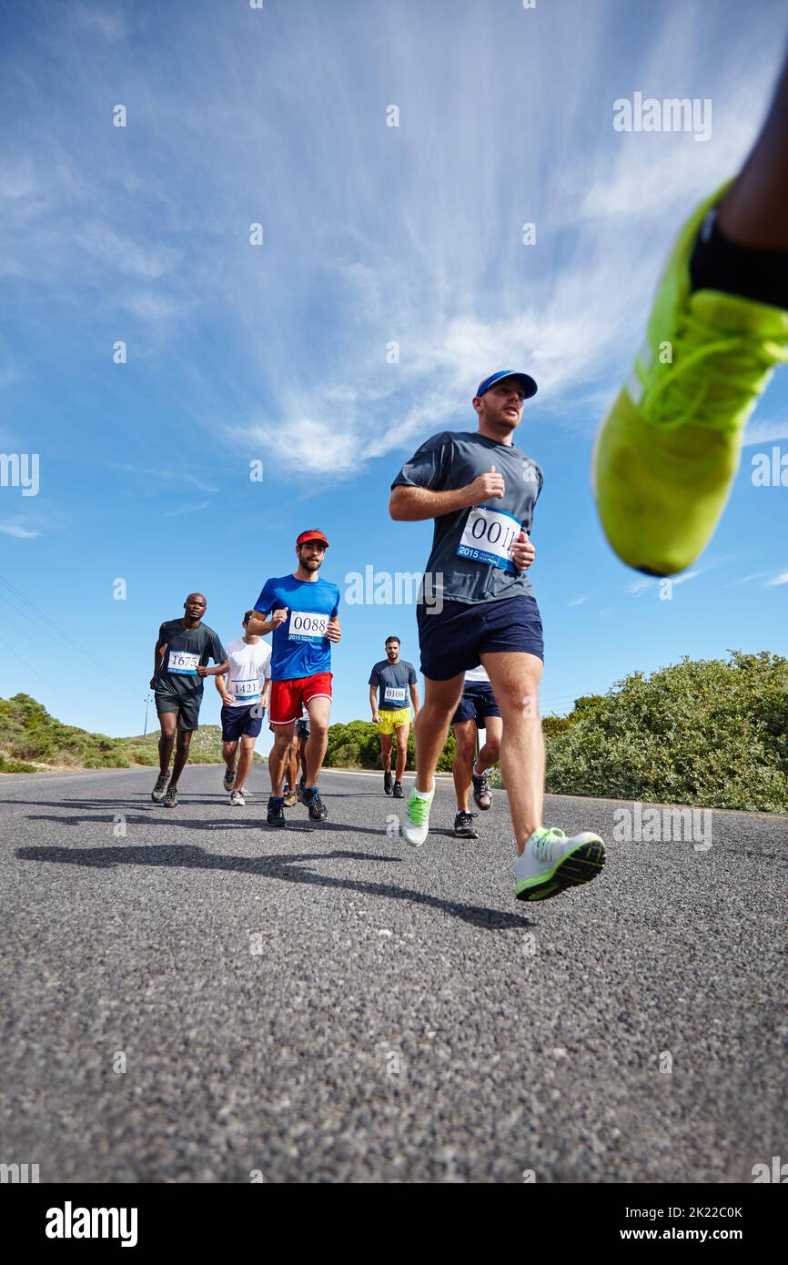 Race for it. Low angle shot of a group of young men running a marathon ...
