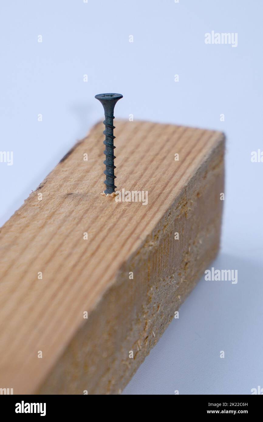 A black screw twisted into a wooden board Stock Photo - Alamy
