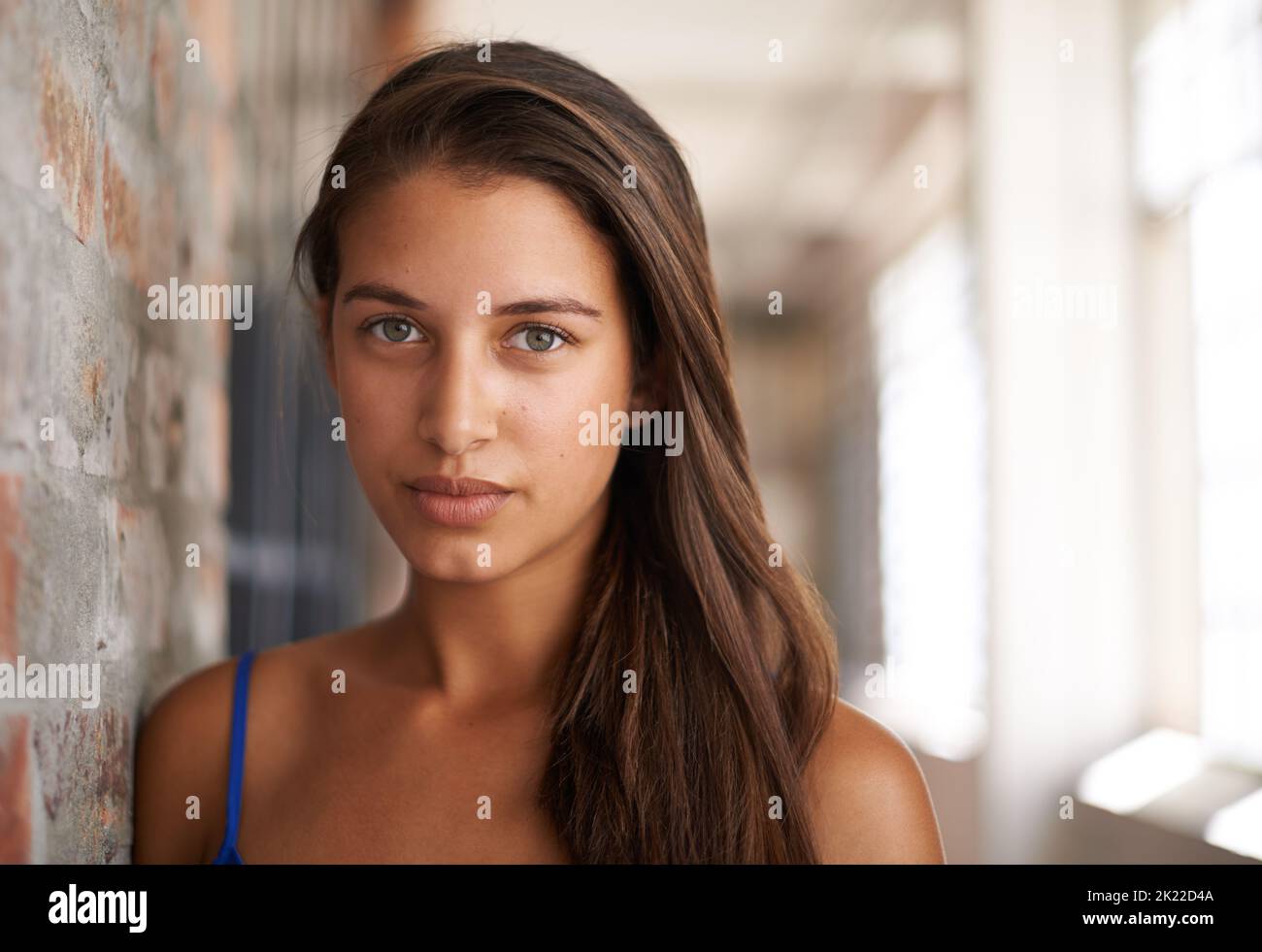 Casual day in the loft. Gorgeous exotic woman leaning against a wall ...