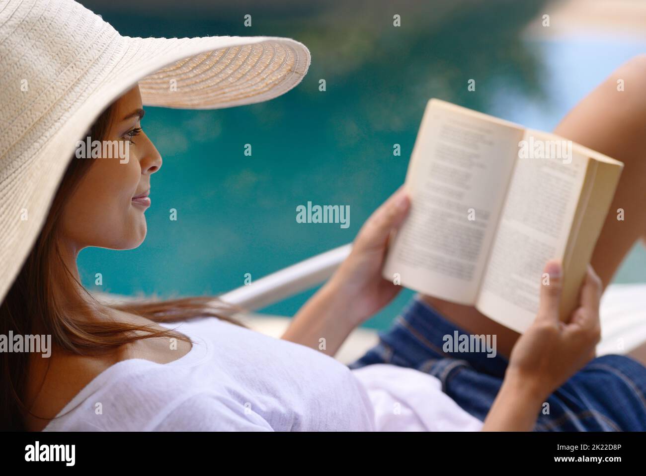 Woman reading book by pool hi-res stock photography and images - Alamy