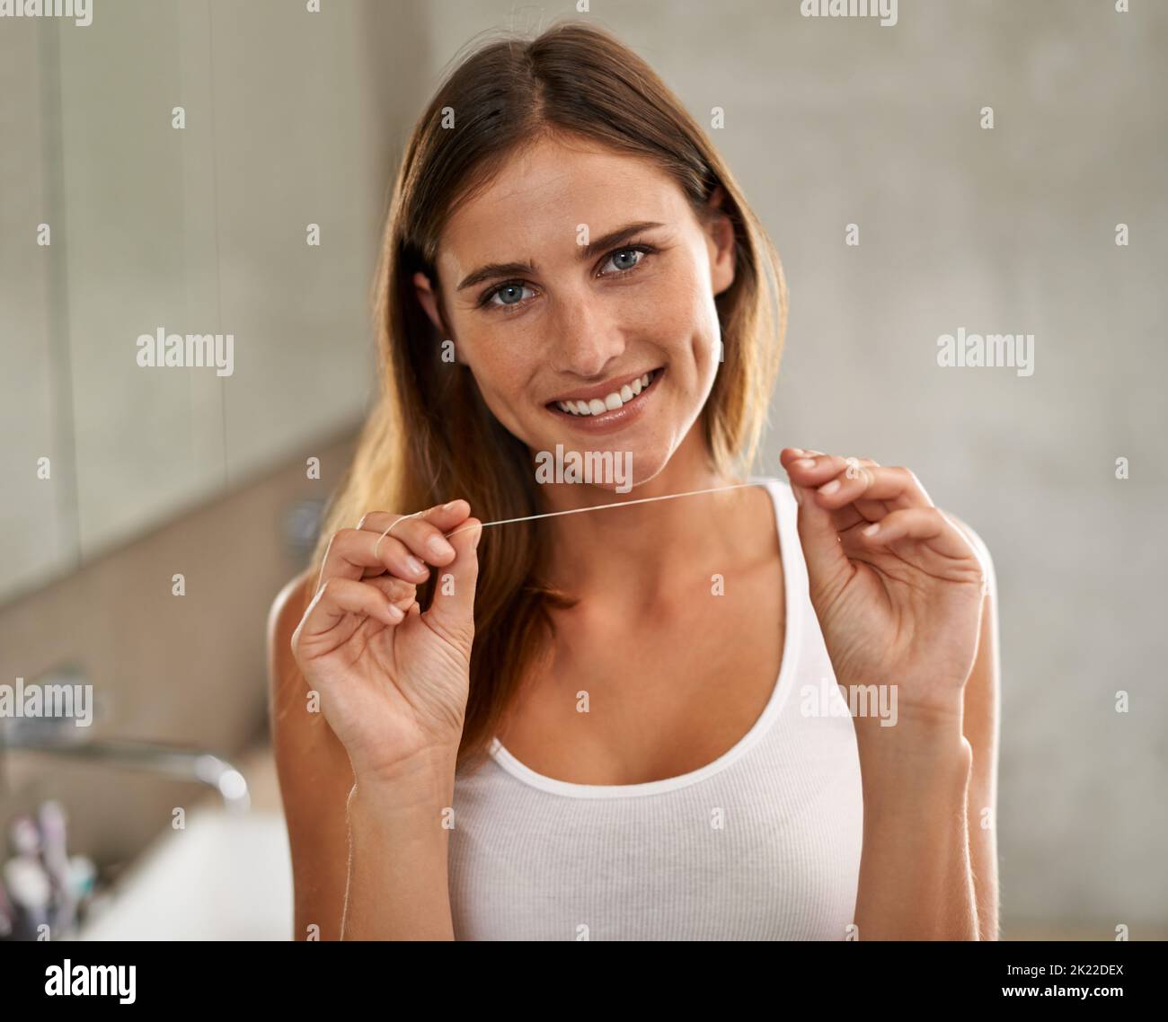 Step one to great teeth. Portrait of a young woman flossing her teeth ...