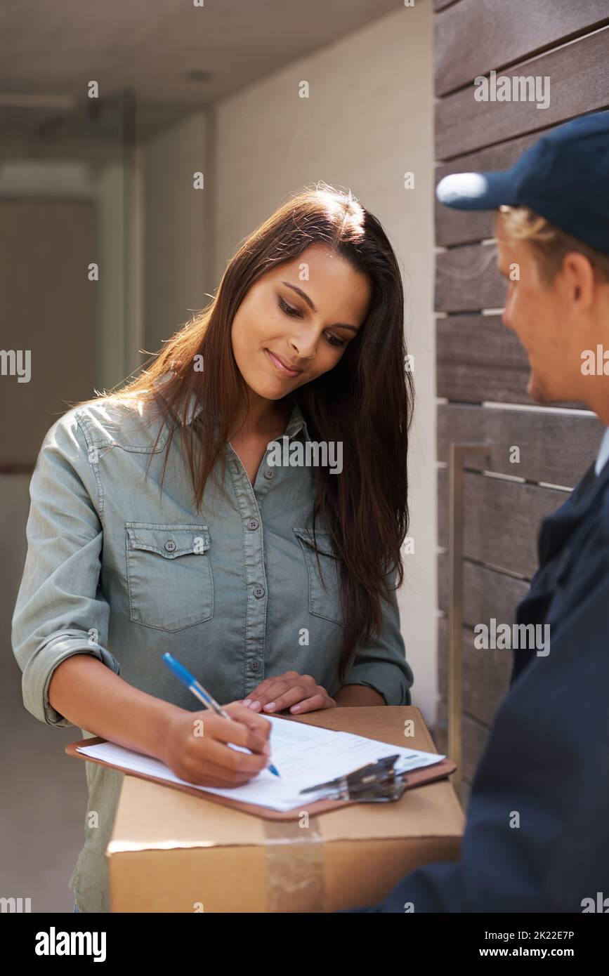 On the dotted line. a young woman signing for a delivery Stock Photo ...