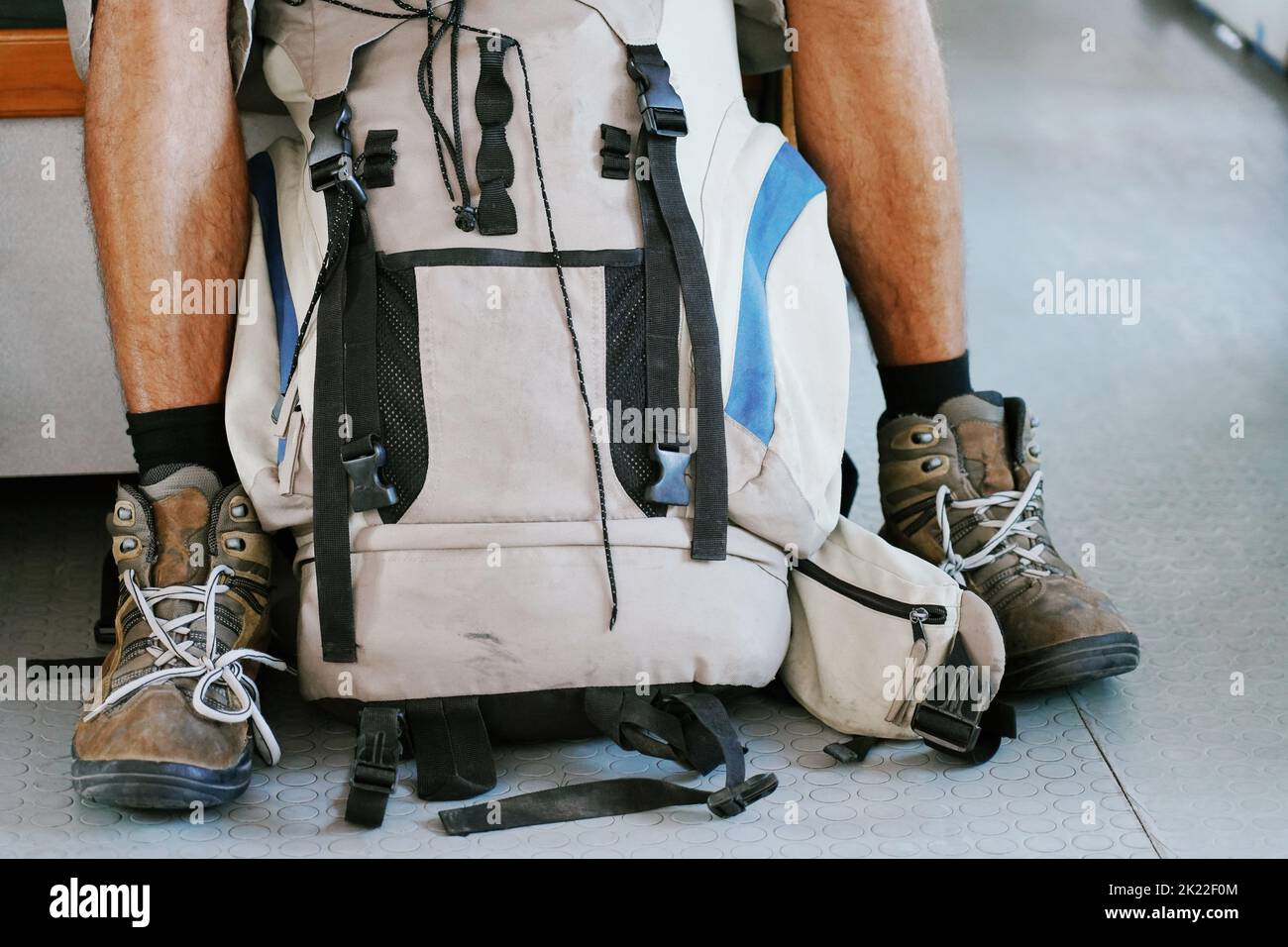 A backpack on the floor in between of the feet Stock Photo - Alamy