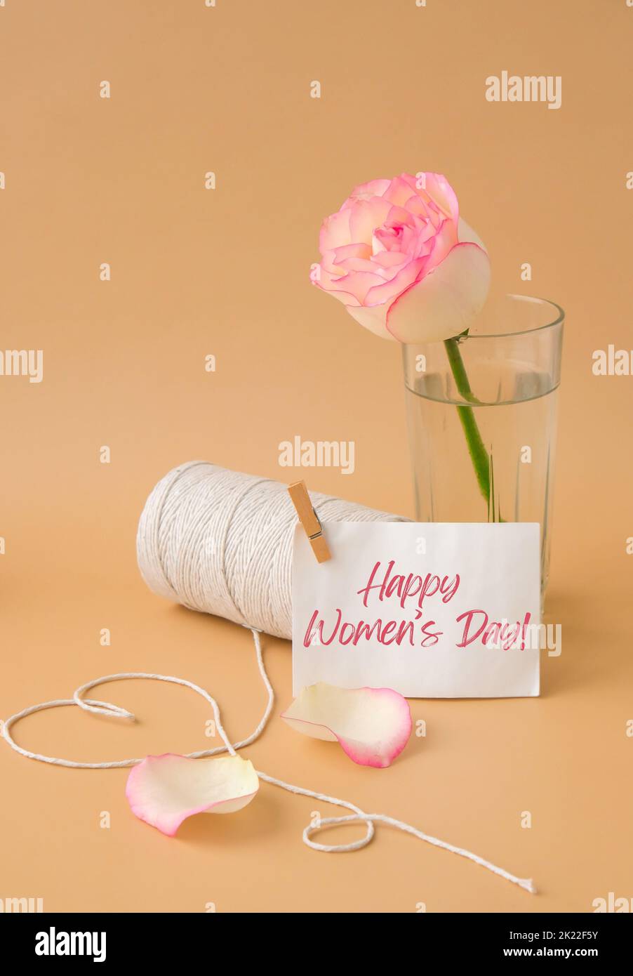 HAPPY WOMENS DAY text Tender pink roses with spool of white cotton rope ...