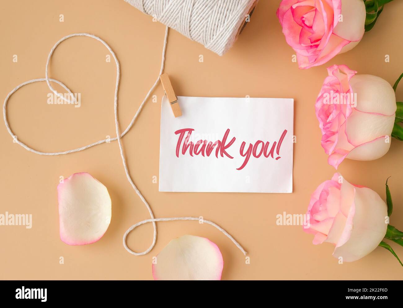 Tender pink roses with spool of white cotton rope in heart shape on ...