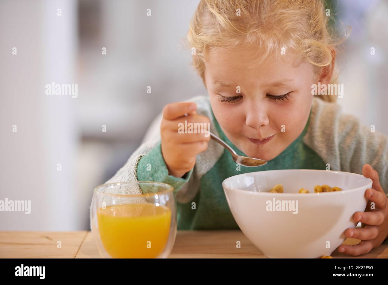 She takes care of her own breakfast in the morning. a cute little girl eating breakfast at home ...