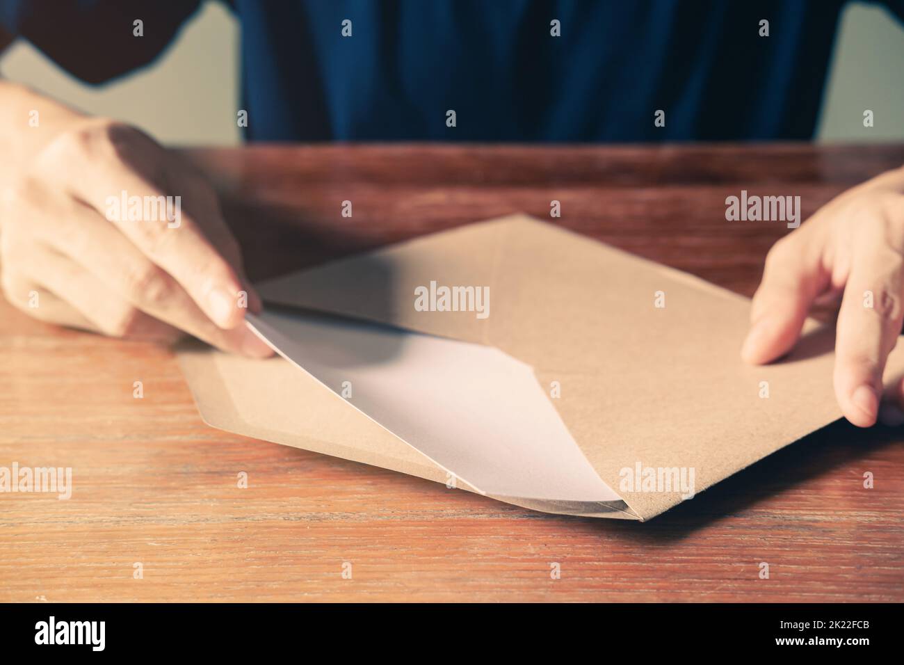 Close-up of Beautiful man hands opening envelope on the brown wooden ...