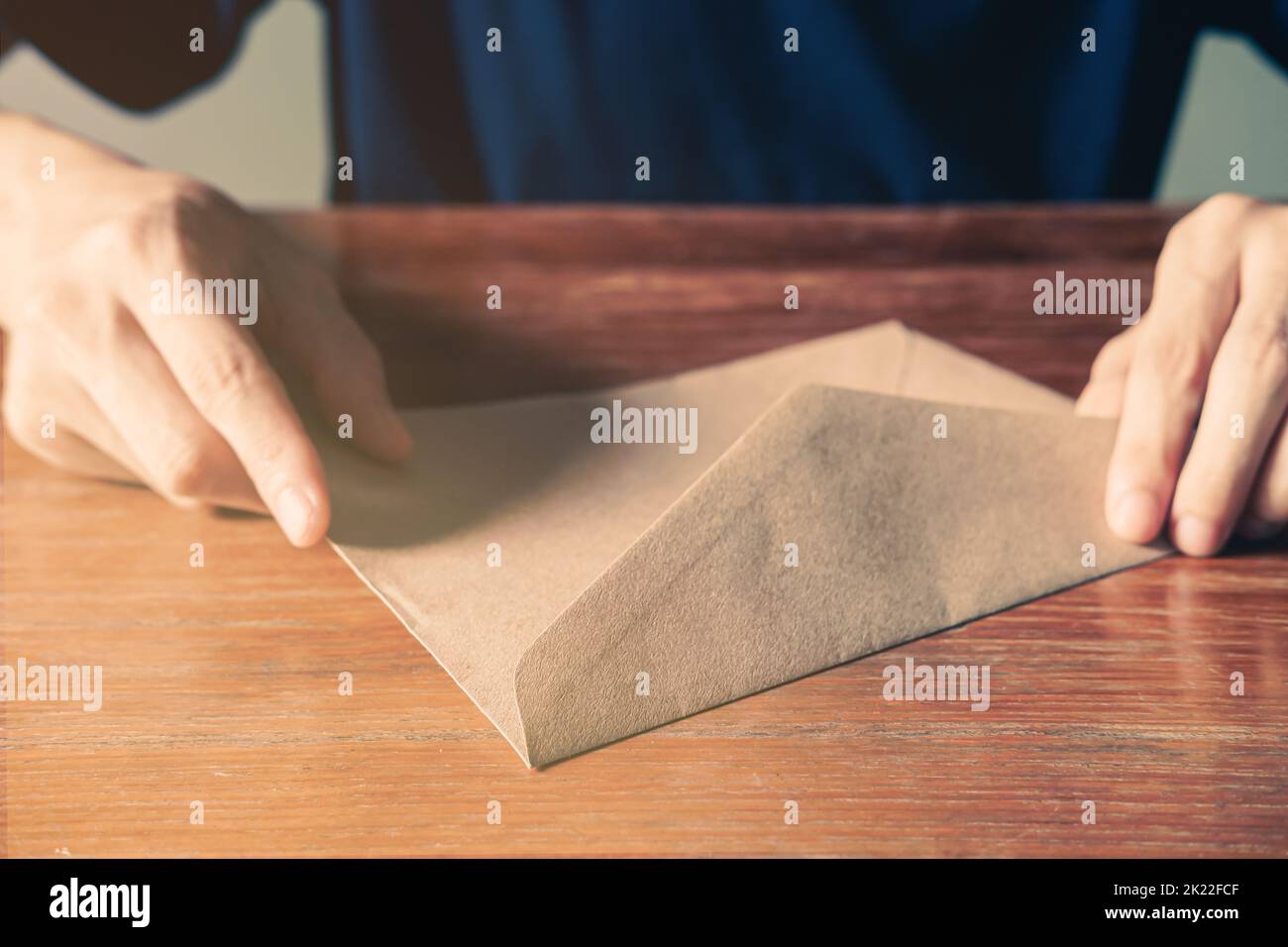 Close-up of Beautiful man hands opening envelope on the brown wooden ...