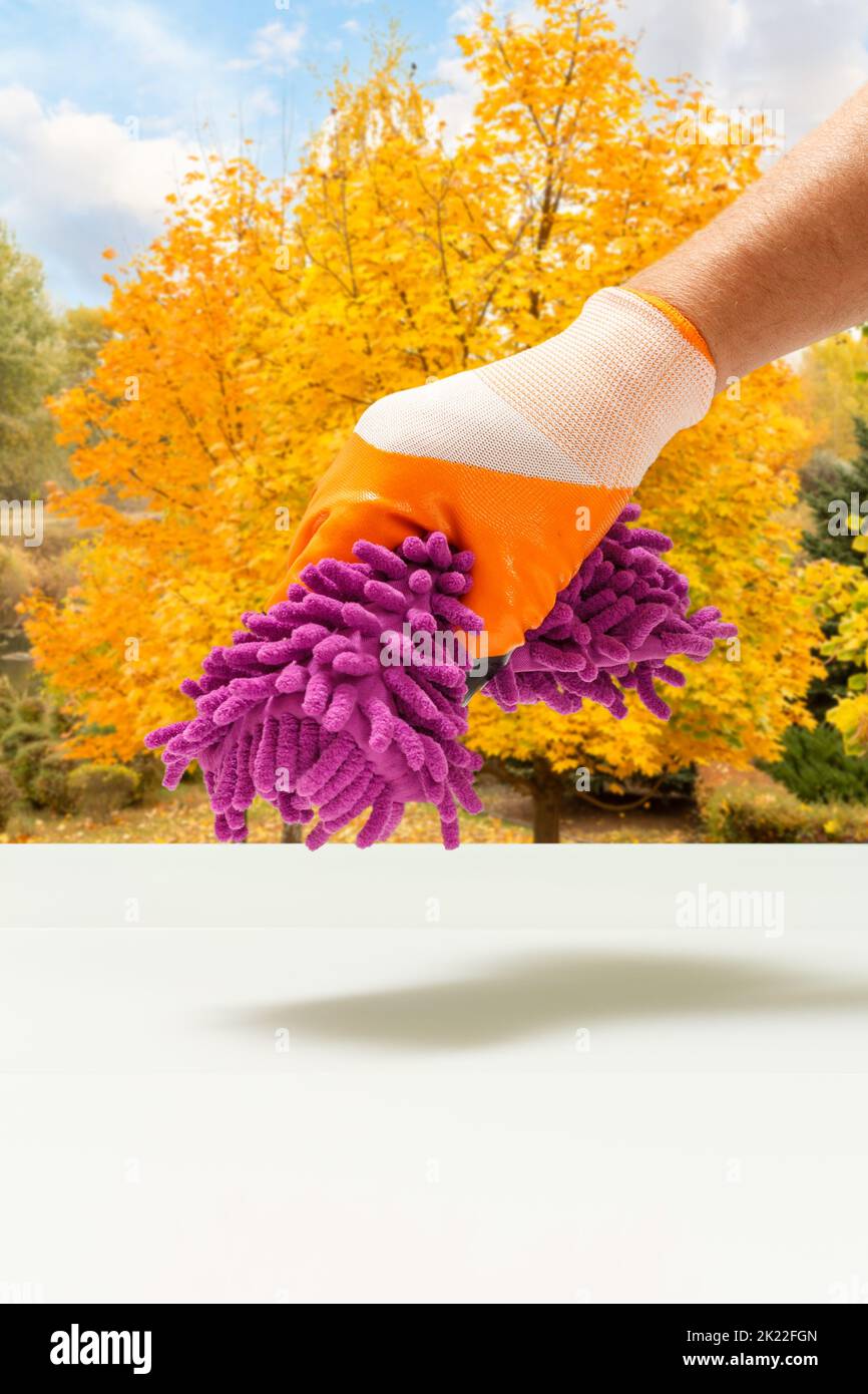 Hand in a rubber glove holding a rag with blurred autumn trees on the ...