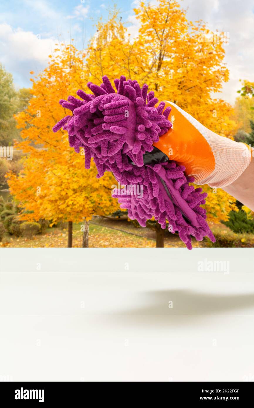 Hand in a rubber glove holding a rag with blurred autumn trees on the ...