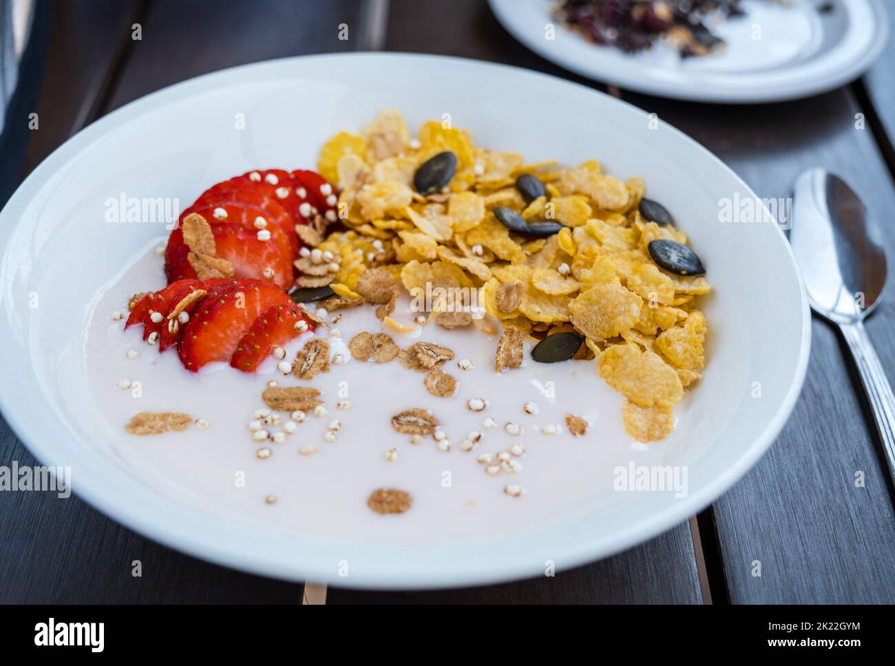 Yogurt bowl with fresh sliced strawberries and dry corn flakes ...