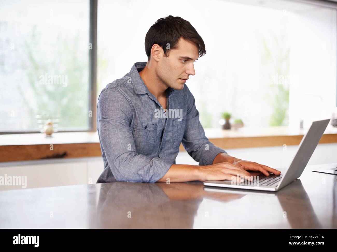 Connecting with the world. a young man using his laptop at home Stock ...
