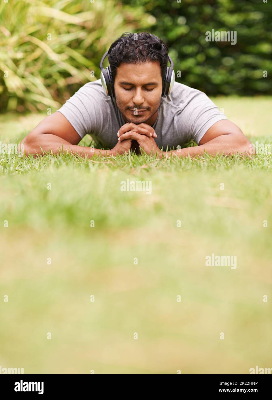 Not a care...a young man lying on some grass wearing headphones Stock ...