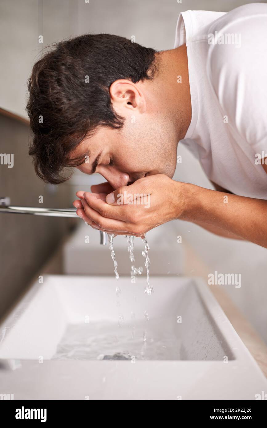 Enjoying some refreshingly cool water. a man washing his face in the bathroom Stock Photo - Alamy
