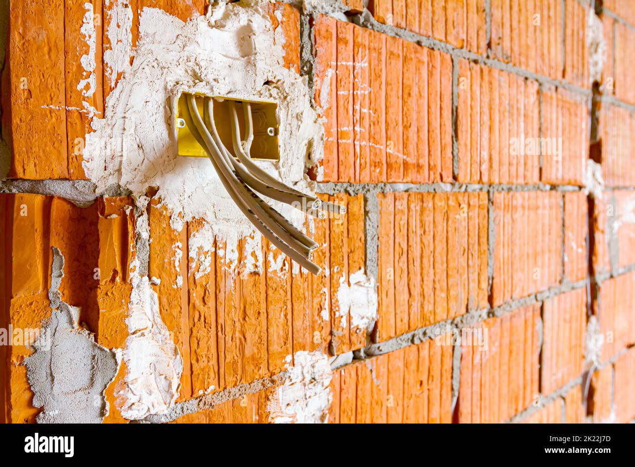 Cables are hanging from junction box placed on the wall of building ...