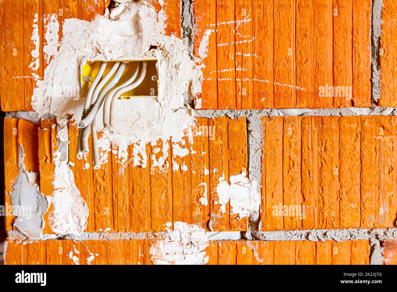 Cables are hanging from junction box placed on the wall of building ...