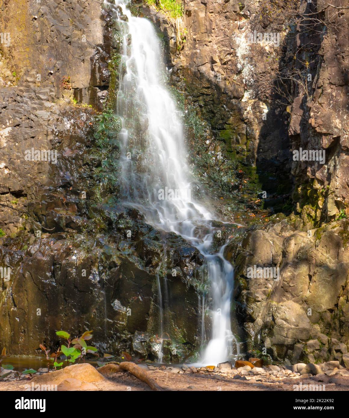 A vertical shot of a splashing cascading waterfall in the mountains ...
