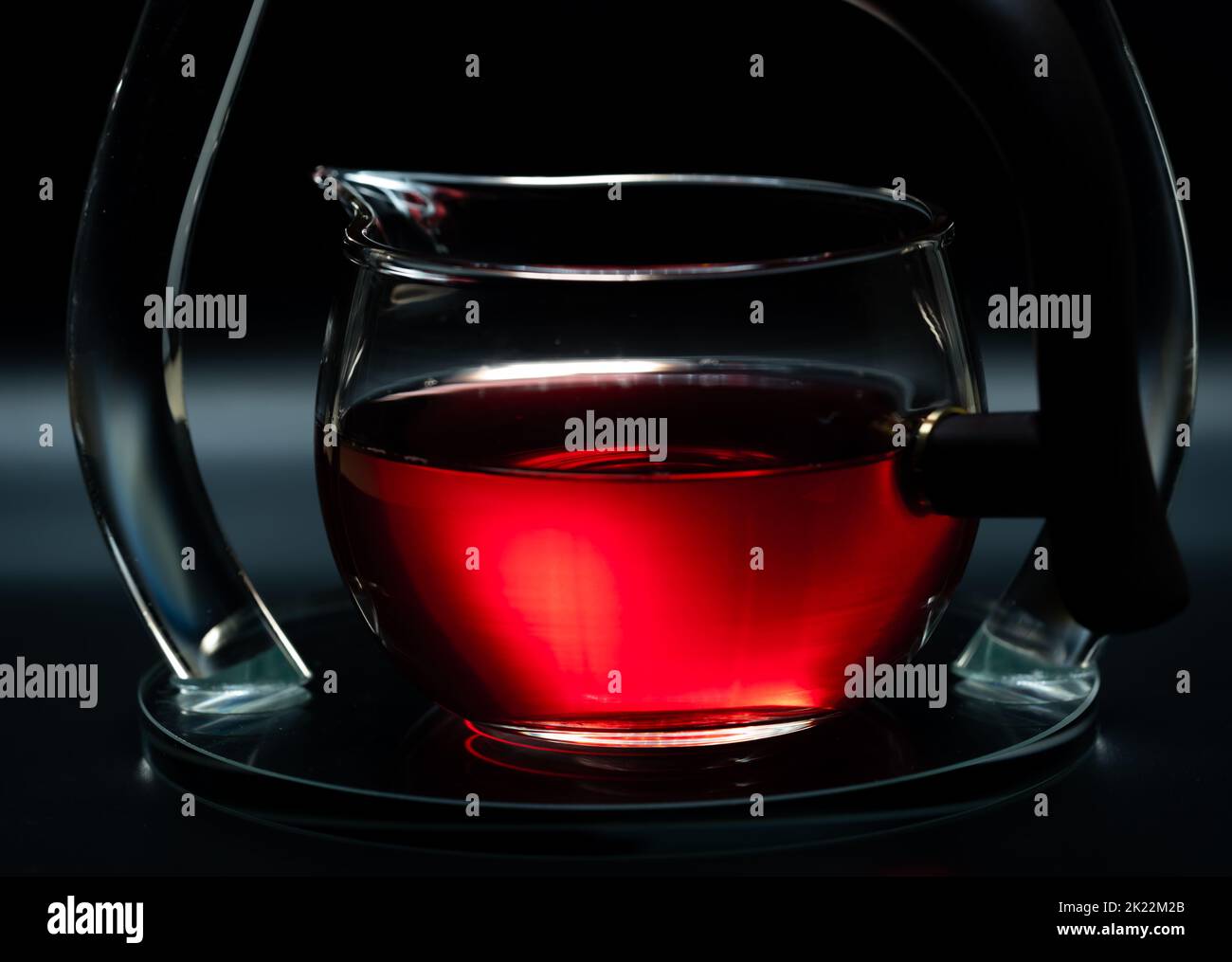 A closeup shot of a teapot with red liquid on a dark background Stock ...