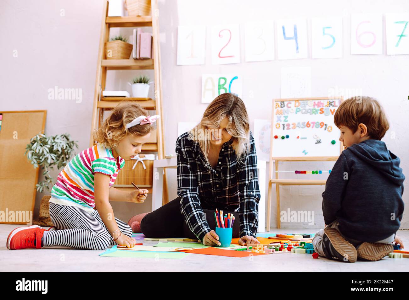 Kind teacher conduct lesson for little children while sitting on floor ...