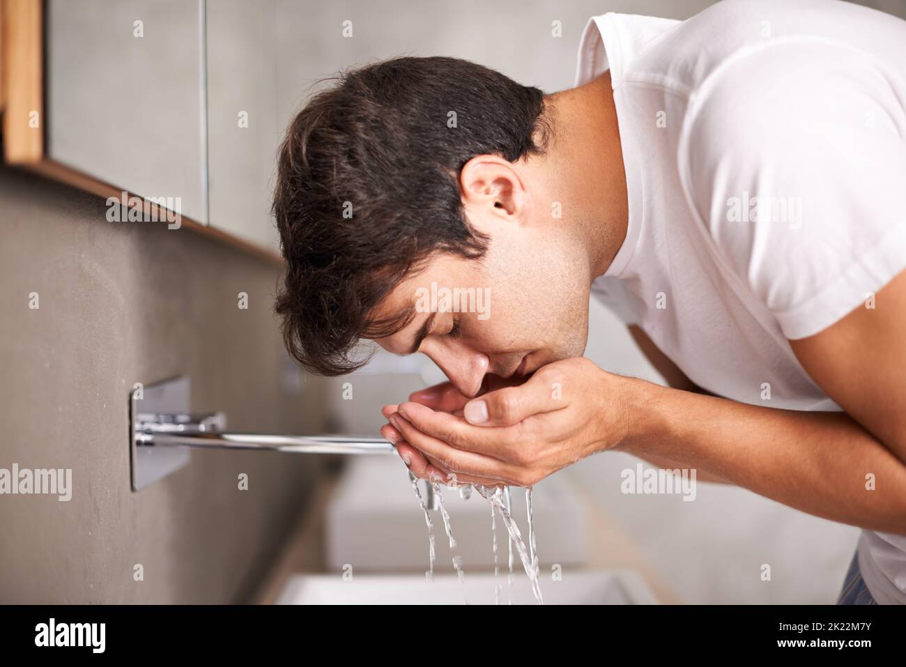 Cleaning away the previous nights sleep. a young man washing his face in his bathroom sink Stock ...