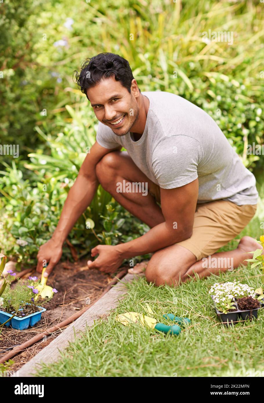 When the green-fingers kick in. Portrait of a young man gardening in ...