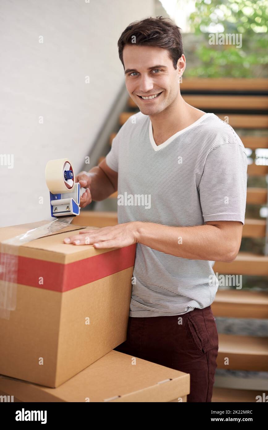 Packing up and rearing to go. A happy young man packing cardboard boxes ...