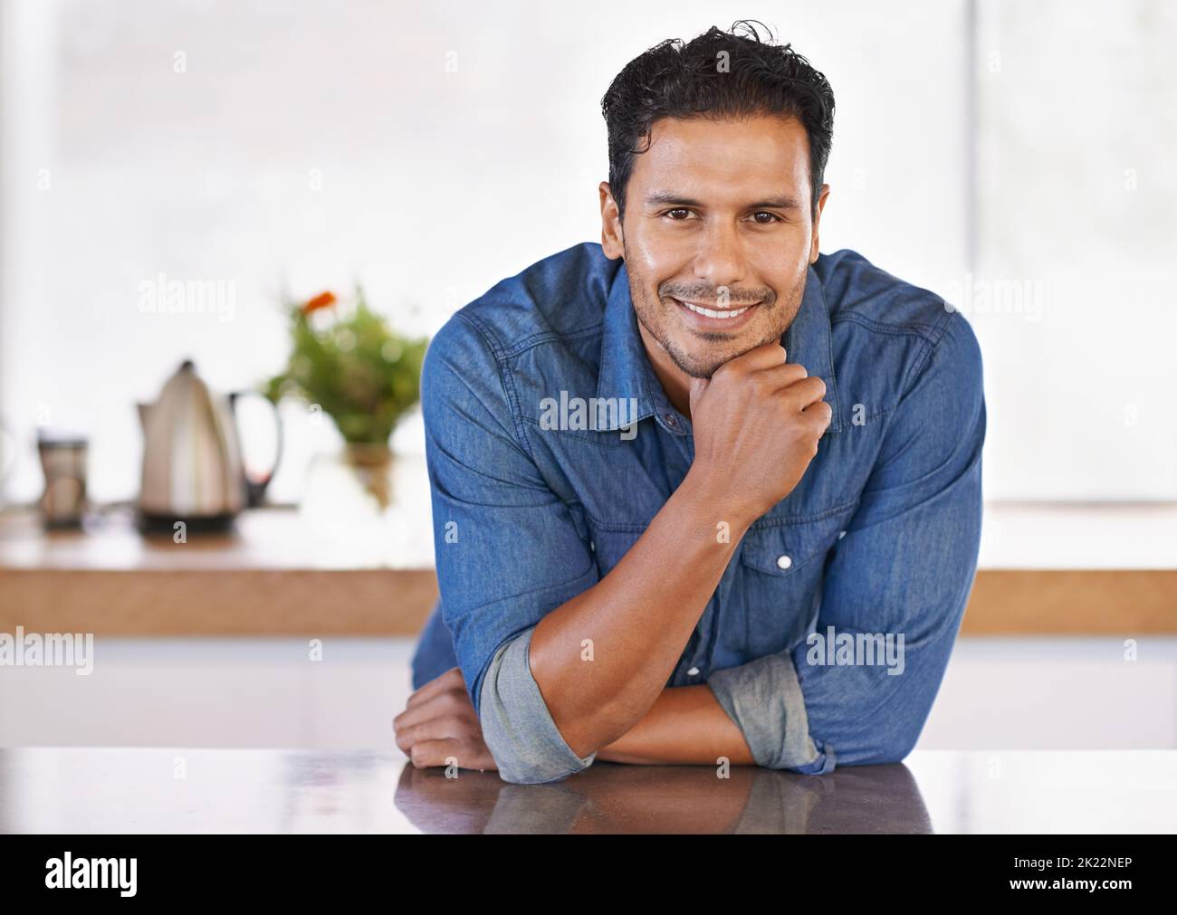 He feels at home in the kitchen. Portrait of a handsome young man ...