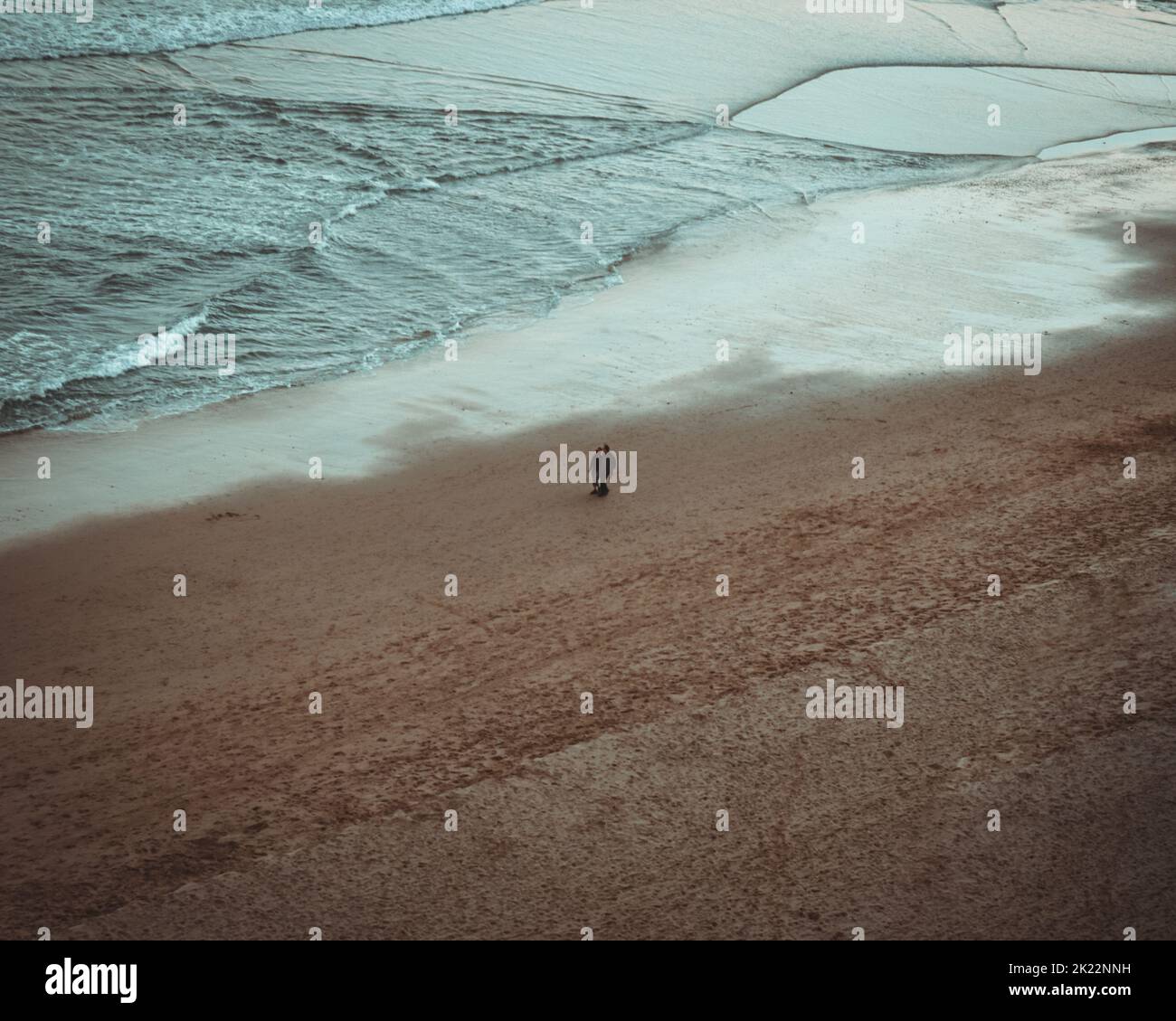 An aerial view of people walking on sandy beach on a cold windy day ...