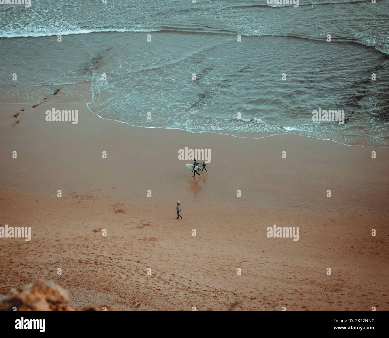 An aerial view of people walking on sandy beach on a cold windy day ...