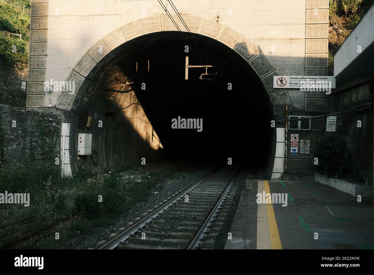 A railway tunnel in Italy with sunlight falling on it and a sign on the ...